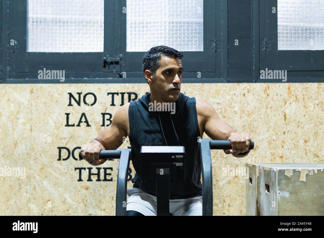 Focused male exercising on air bike during intense functional workout ...