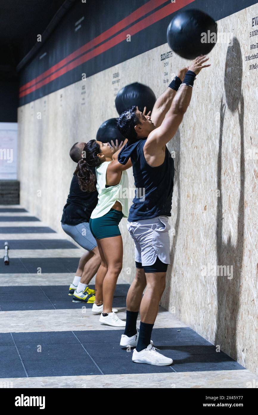 Full body side view group of Hispanic sportspeople in activewear standing near wall with heavy ...