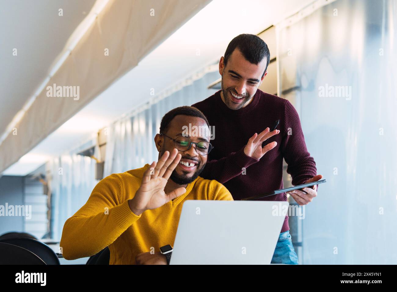 Positive diverse employees waving hands while looking at screen of ...