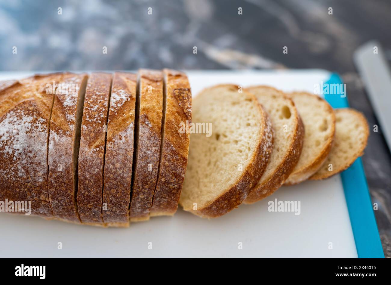 Closeup of loaf of homemade artisan wheat bread, partially sliced, with ...