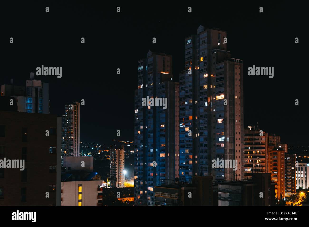 Tall blocks of flats with glowing windows located against dark night ...