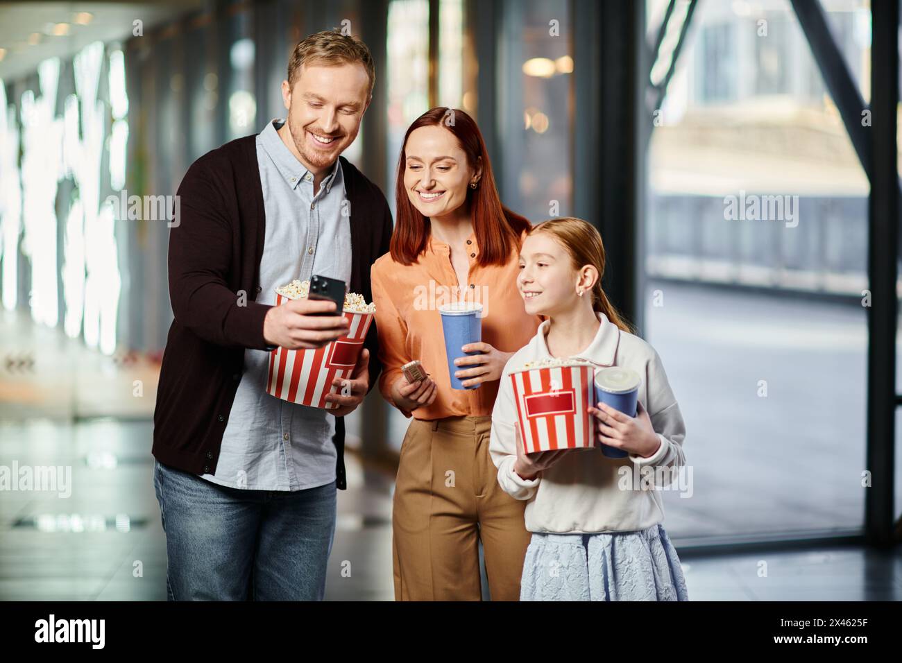 family joyfully holding boxes of popcorn at the cinema, bonding ...
