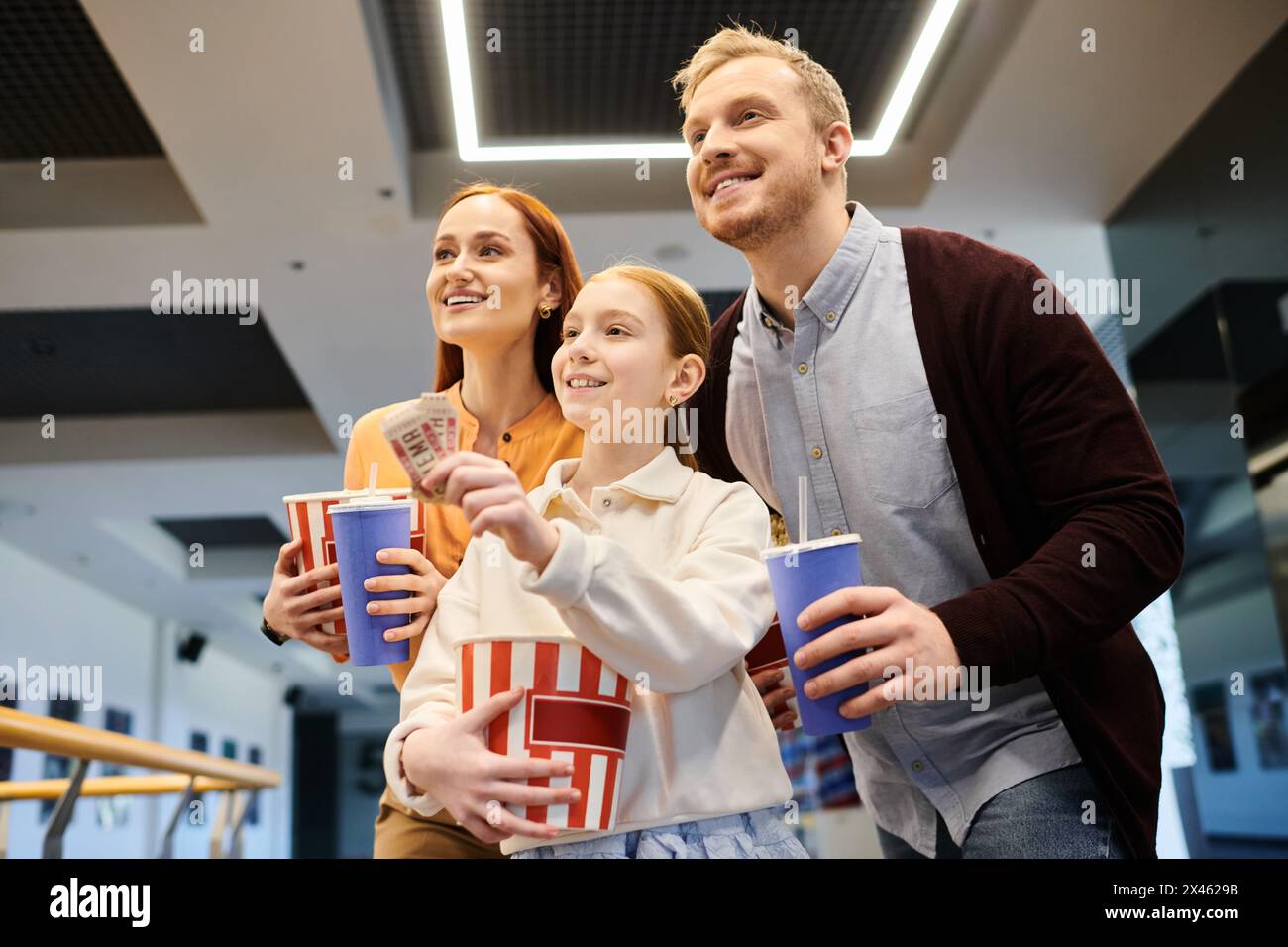 A happy family stands together holding cups, enjoying their time at the ...