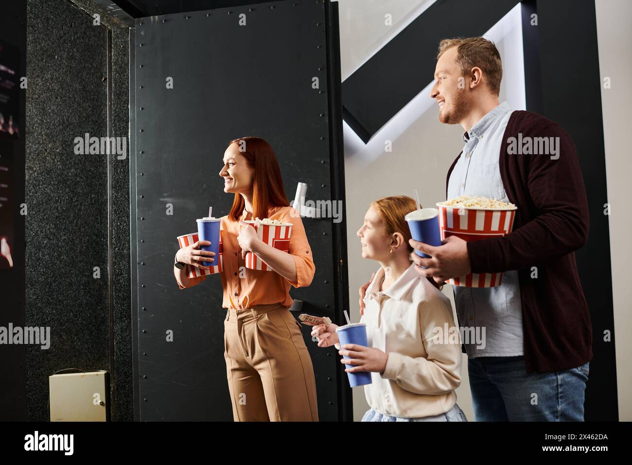 A happy family stands closely together, enjoying a movie night at the ...