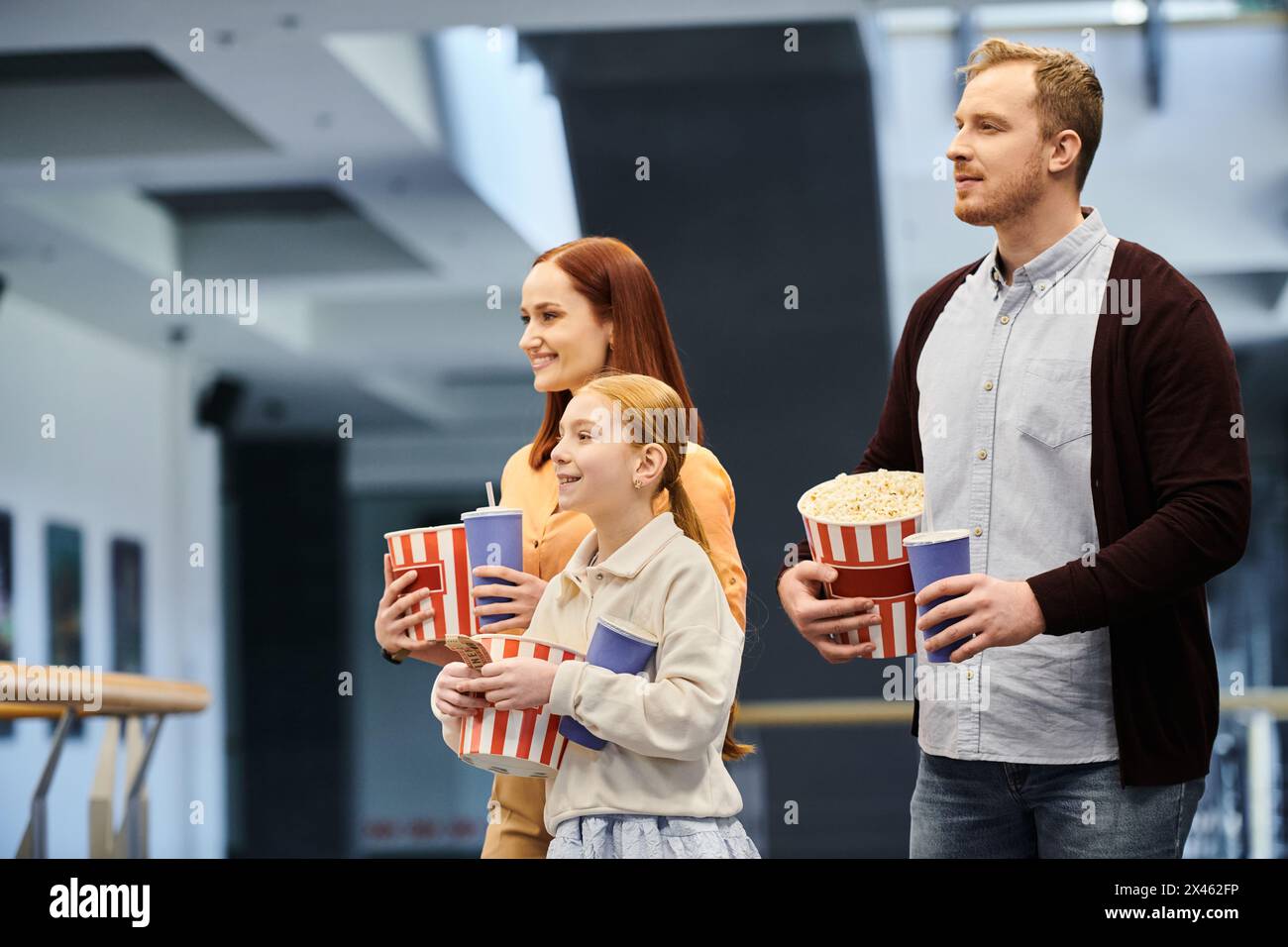 A man, woman, and child happily hold popcorn boxes during a fun family ...