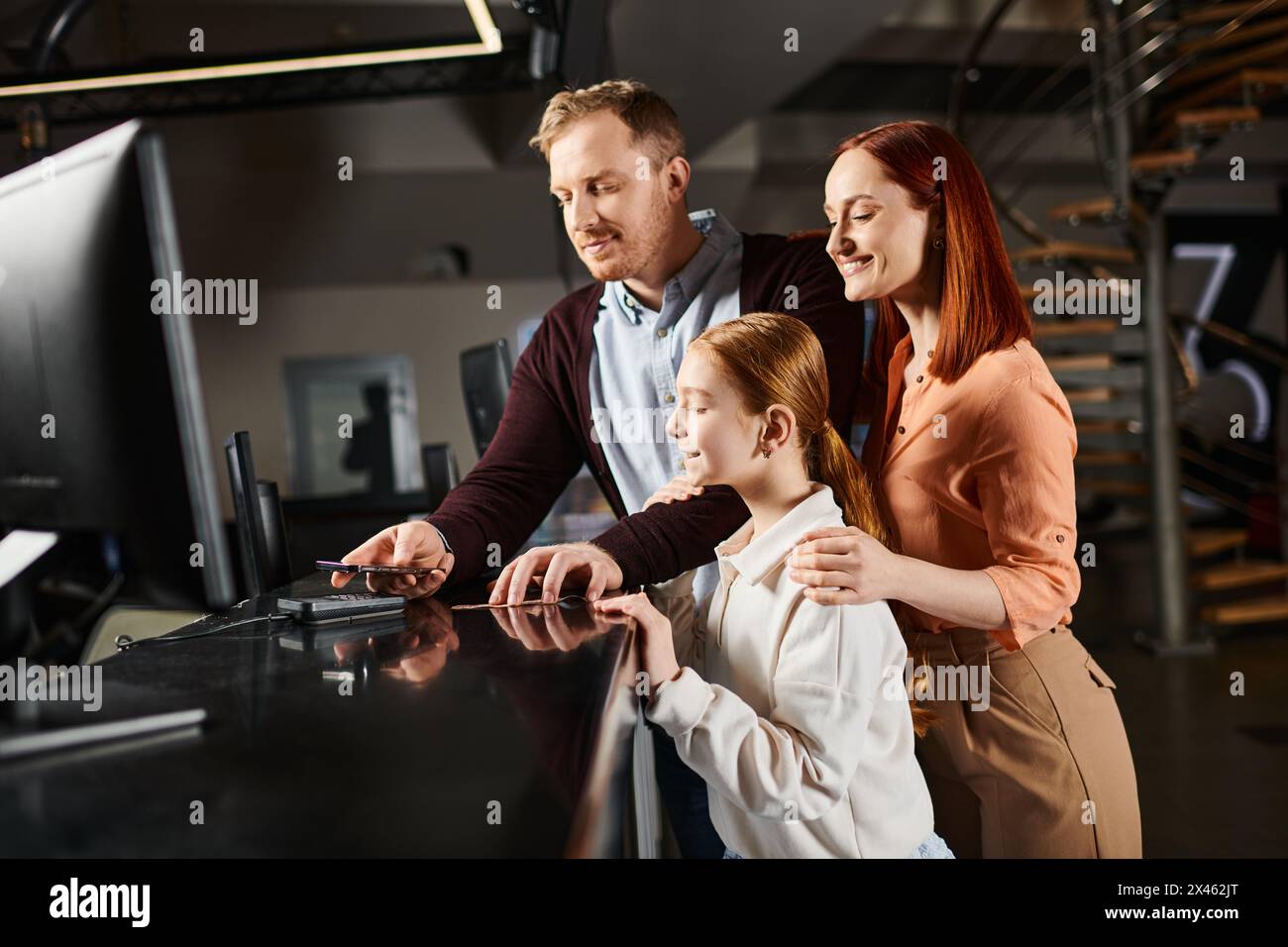 A Man And Two Women Engaging With A Computer Screen Displaying Curiosity And Collaboration In A
