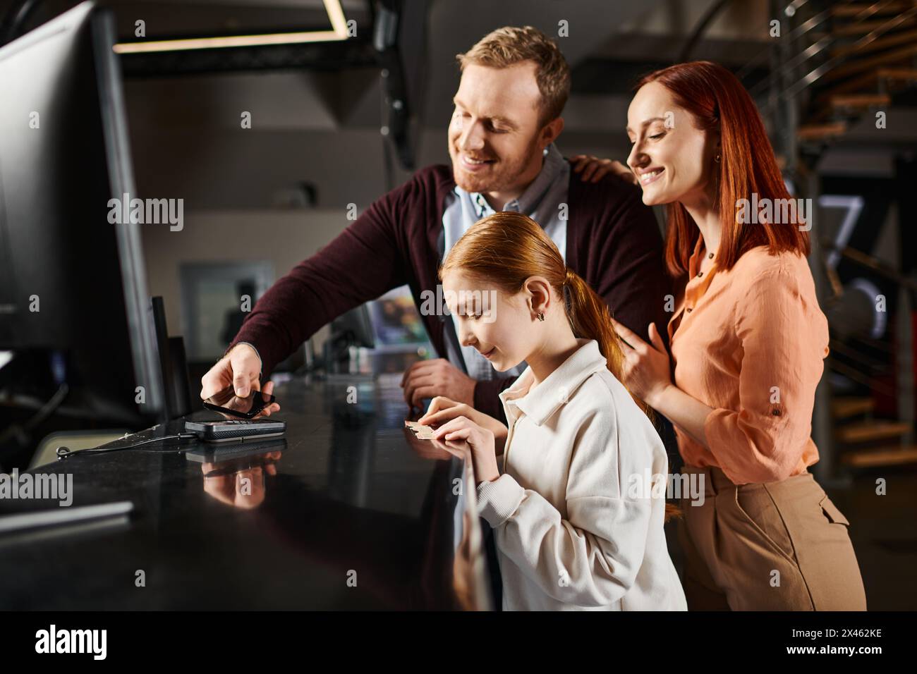 Three people, a happy family, gathered around a computer screen ...