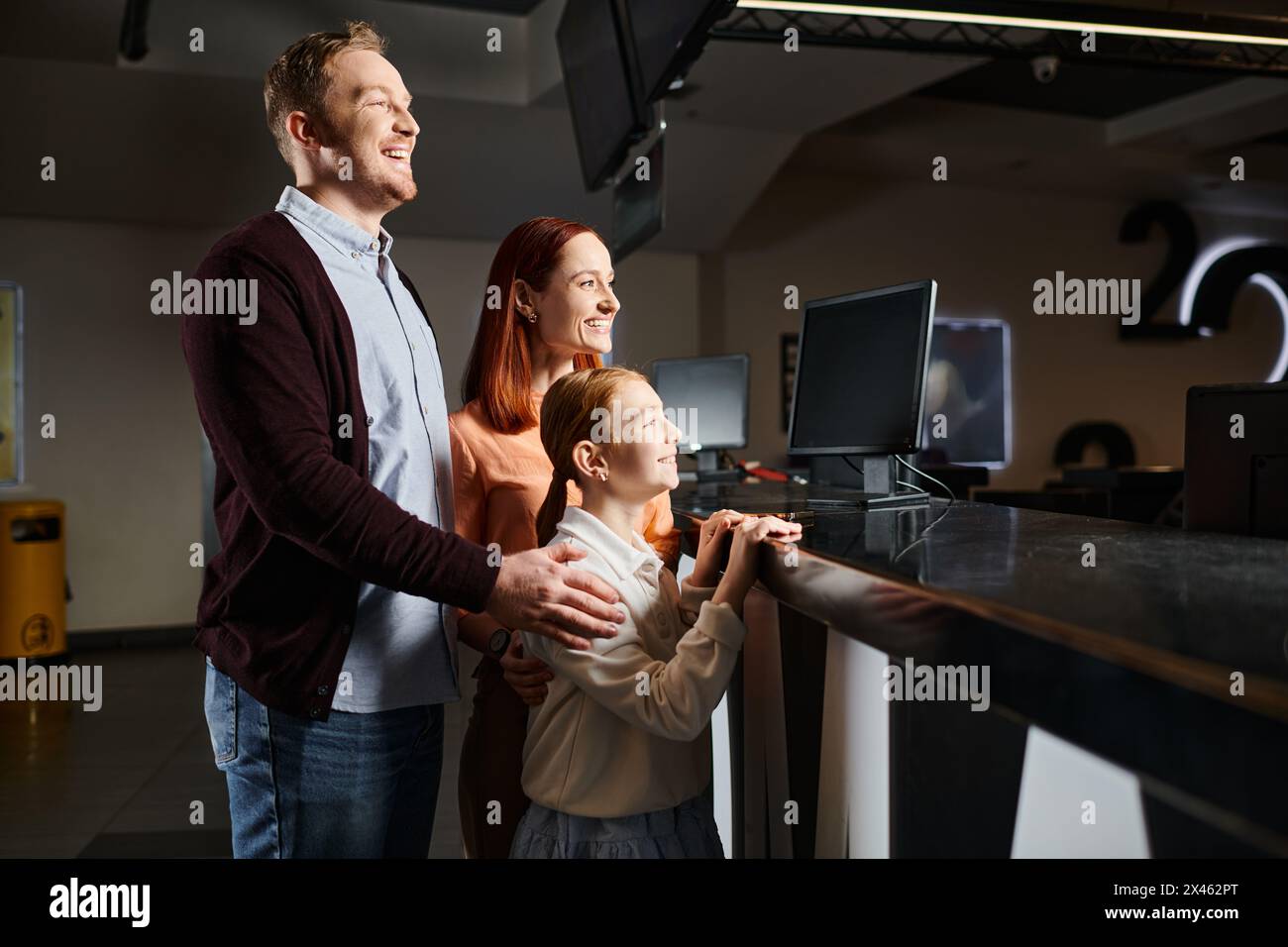A happy man, woman, and child standing at a concession counter in a ...