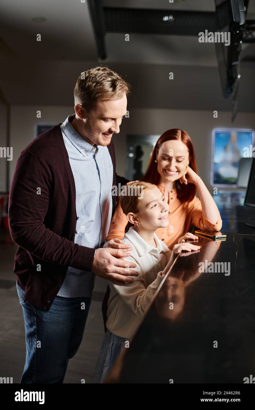 A happy family standing at a concession counter in a cinema, choosing ...