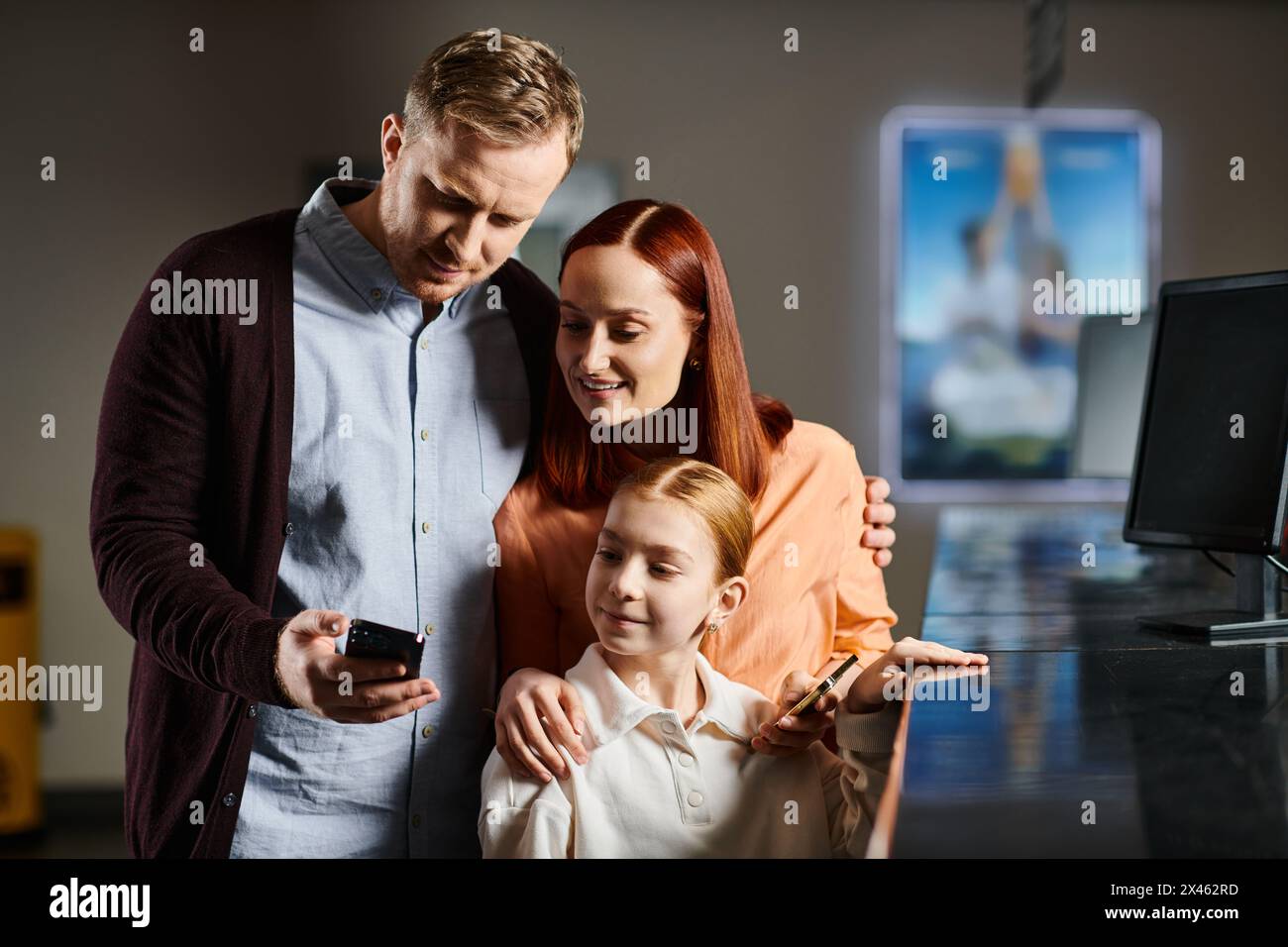 A man and two women, a happy family, stand together at the cinema ...