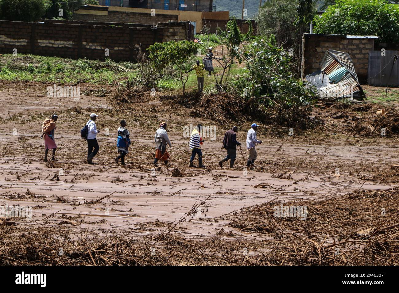 People walk on the mud after a river broke it banks and caused ...