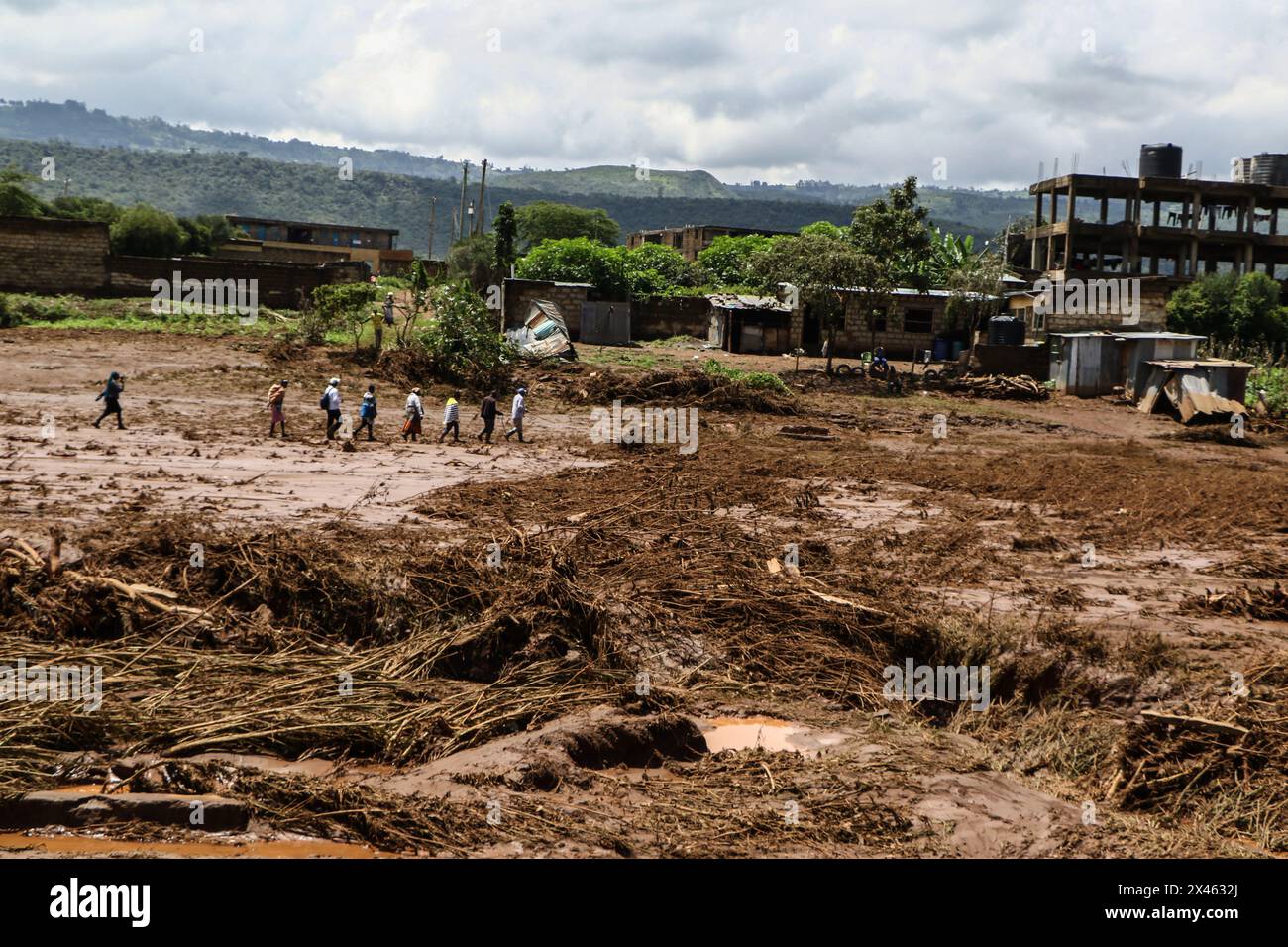 People walk on the mud after a river broke it banks and caused ...