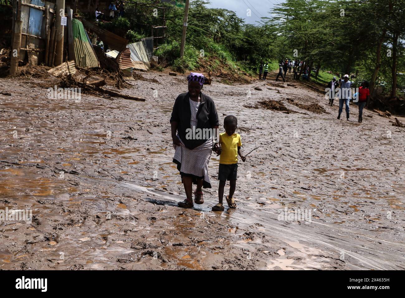 A woman and a child walk on the mud after a river broke it banks and ...