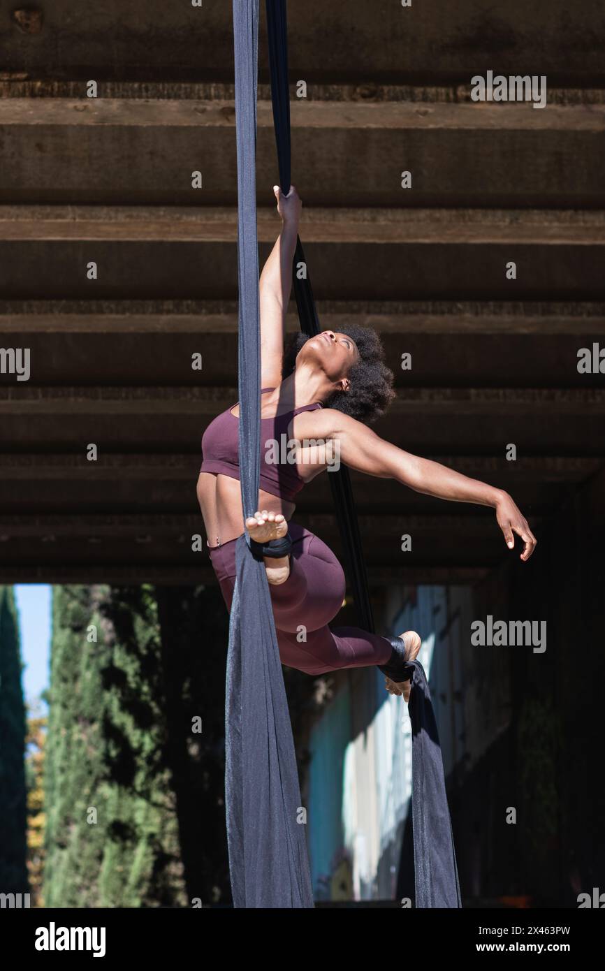 Low angle of flexible African American female doing yoga in aerial ...