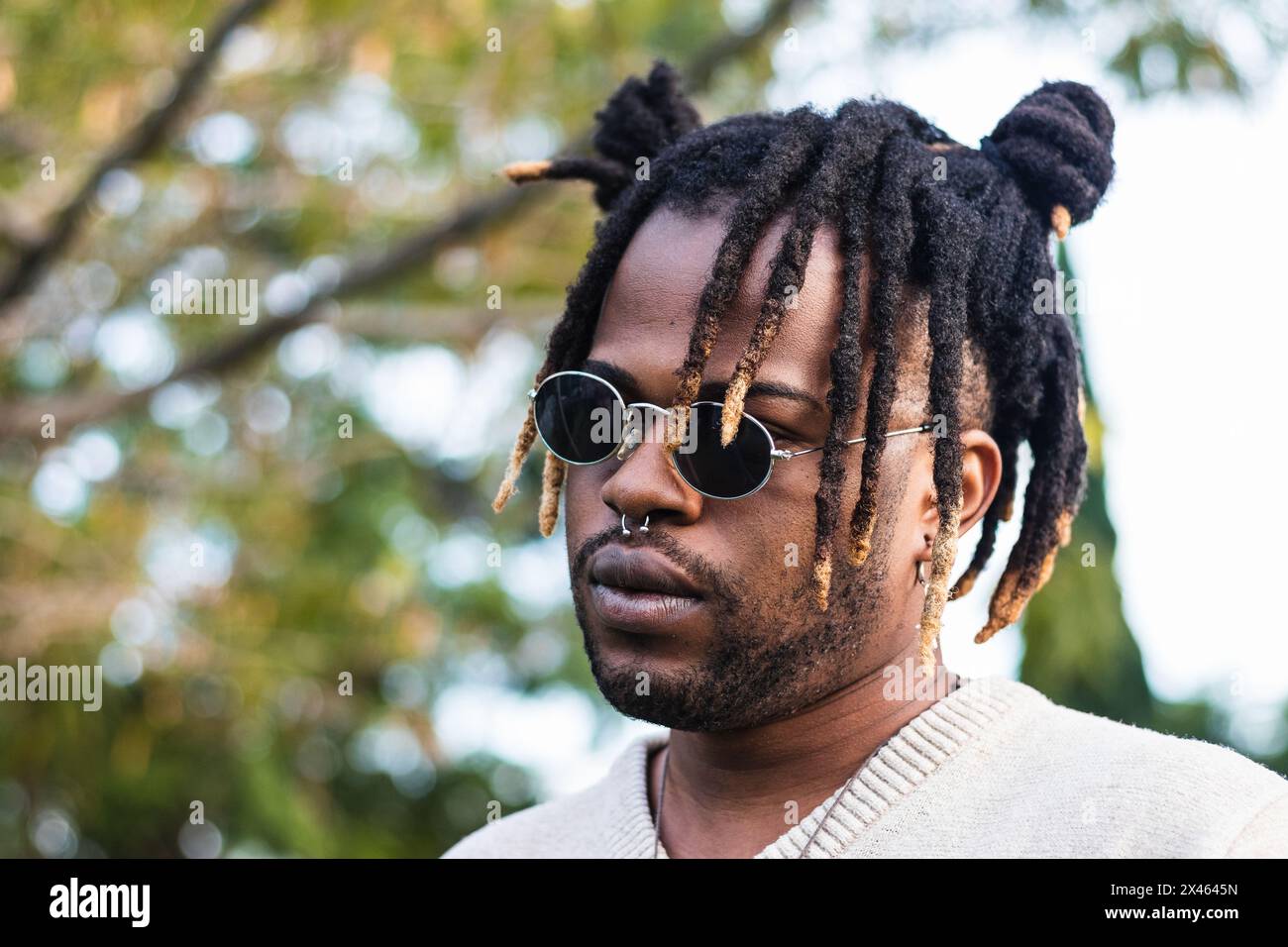 African American man with dreadlocks in bun wearing nose piercing with ...