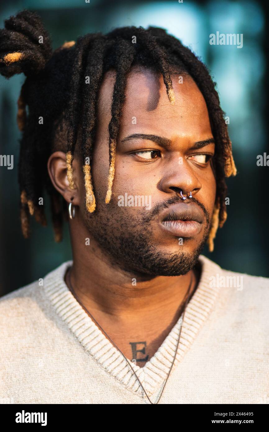African American man with dreadlocks in bun wearing nose piercing on ...