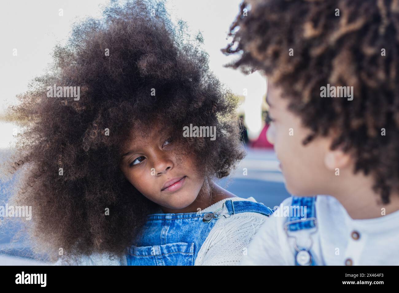 Teen black sister and brother with Afro hair wearing denim overalls ...
