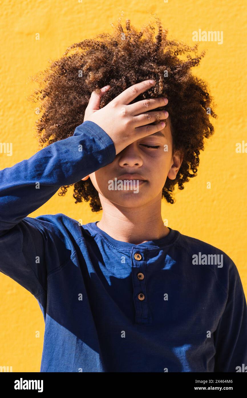 Disappointed curly haired African American teen boy with eyes closed ...