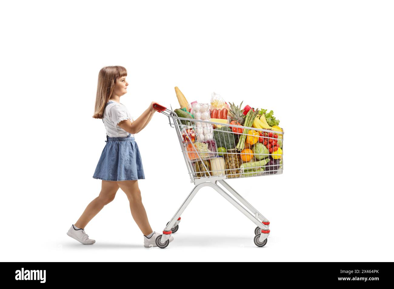 Child pushing a shopping cart with food products isolated on white ...