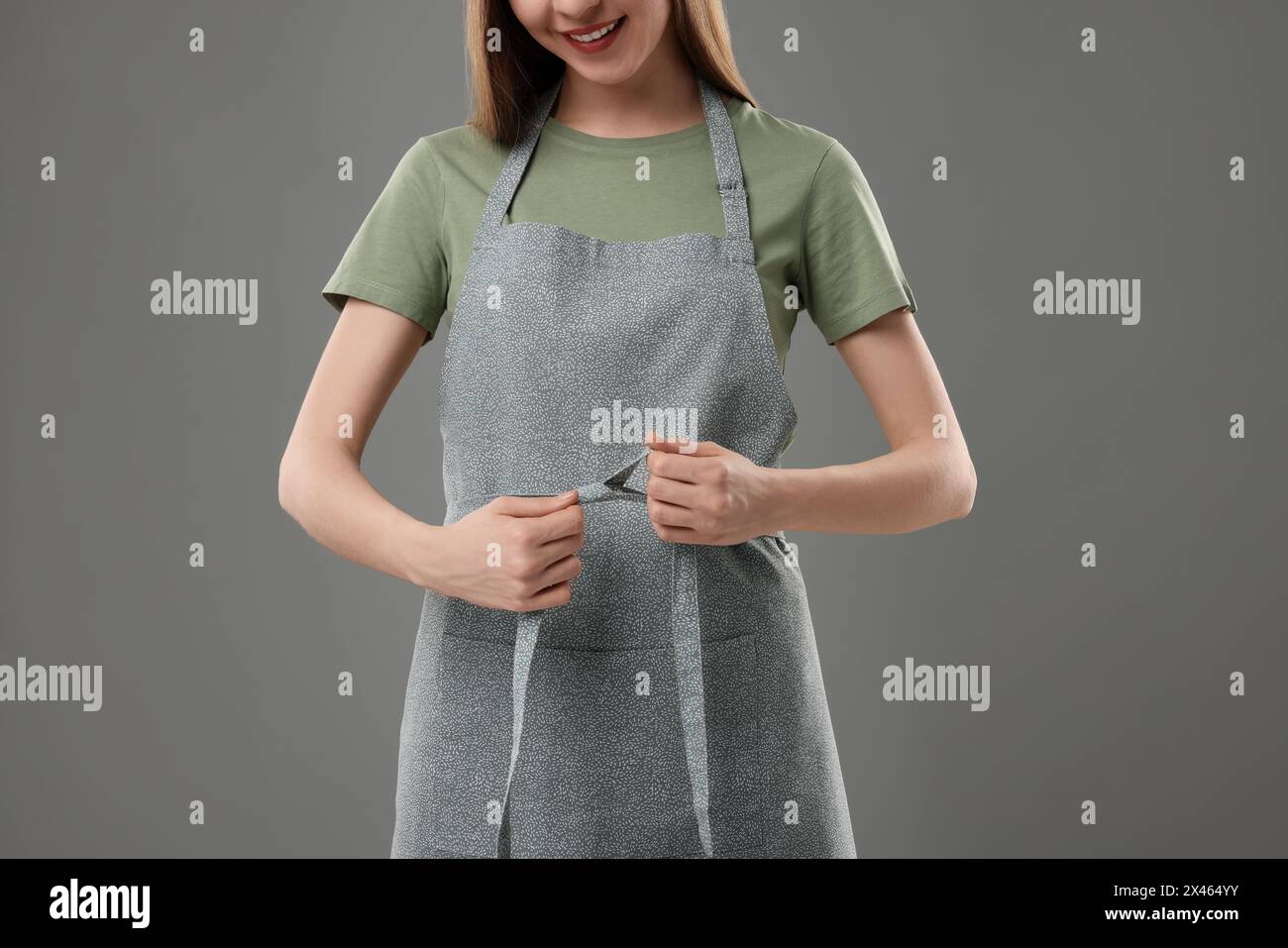 Woman wearing kitchen apron on grey background, closeup. Mockup for ...