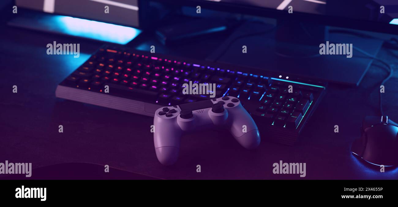 Playing video games. Computer monitor, keyboard, mouse and wireless controller on table indoors ...