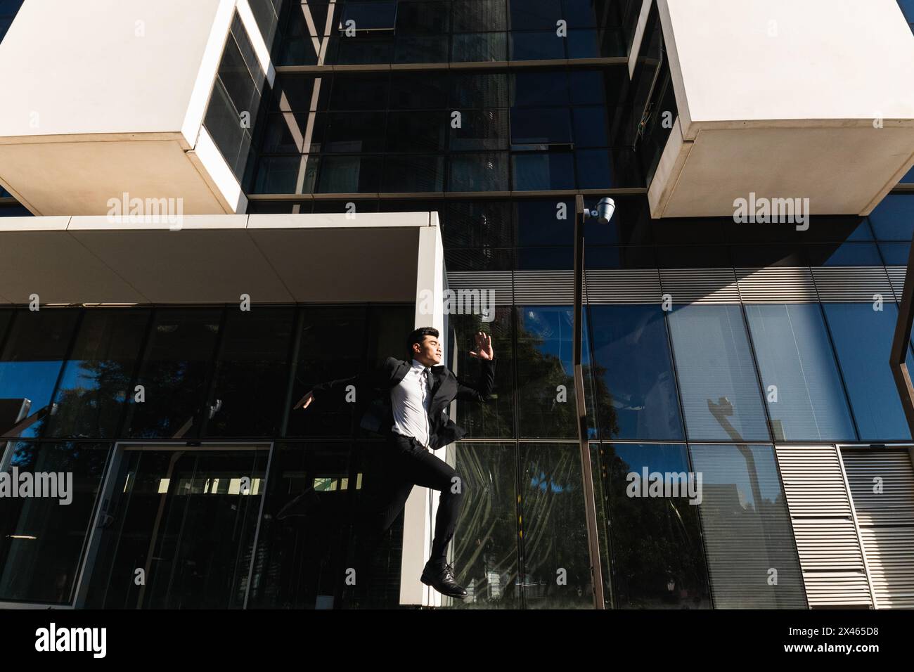 From below of male entrepreneur in formal suit in moment of jumping ...