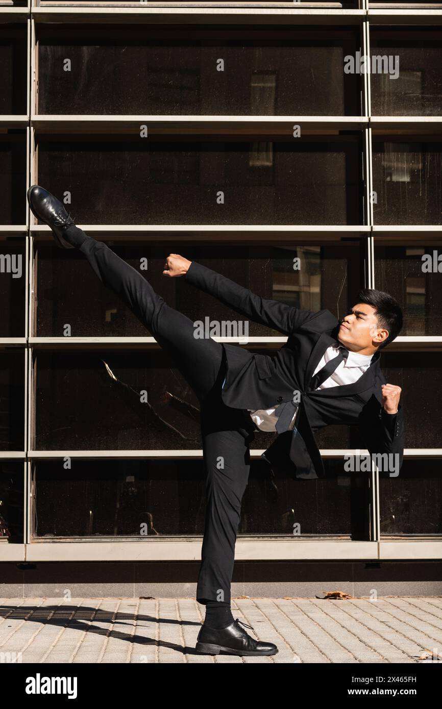 Rebellious Asian male entrepreneur in formal suit kicking air and ...