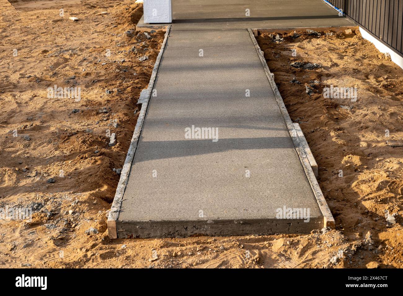 Recently poured concrete sidewalk and surrounding dirt, at a ...