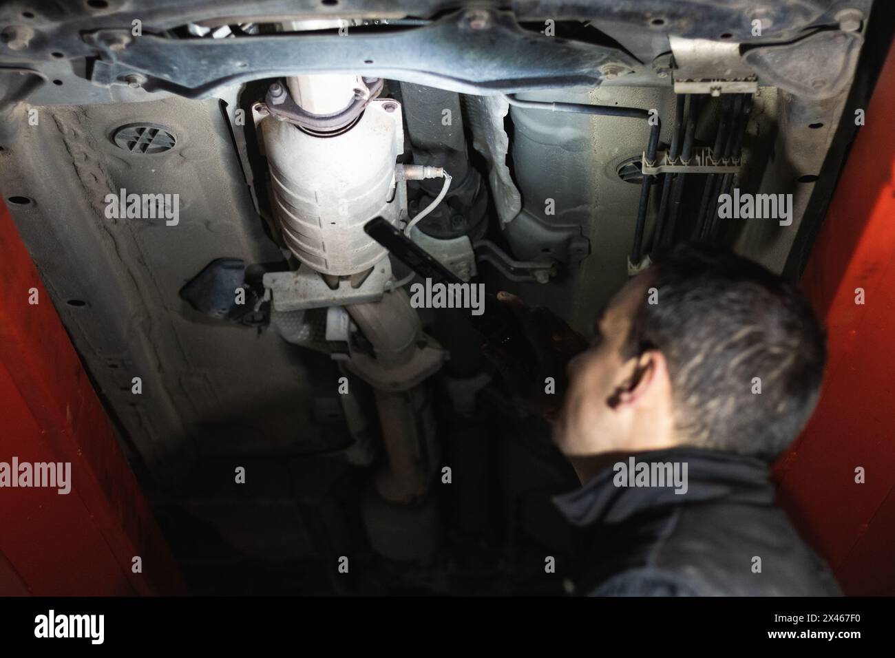 Side view of unrecognizable male mechanic mechanic checking exhaust ...