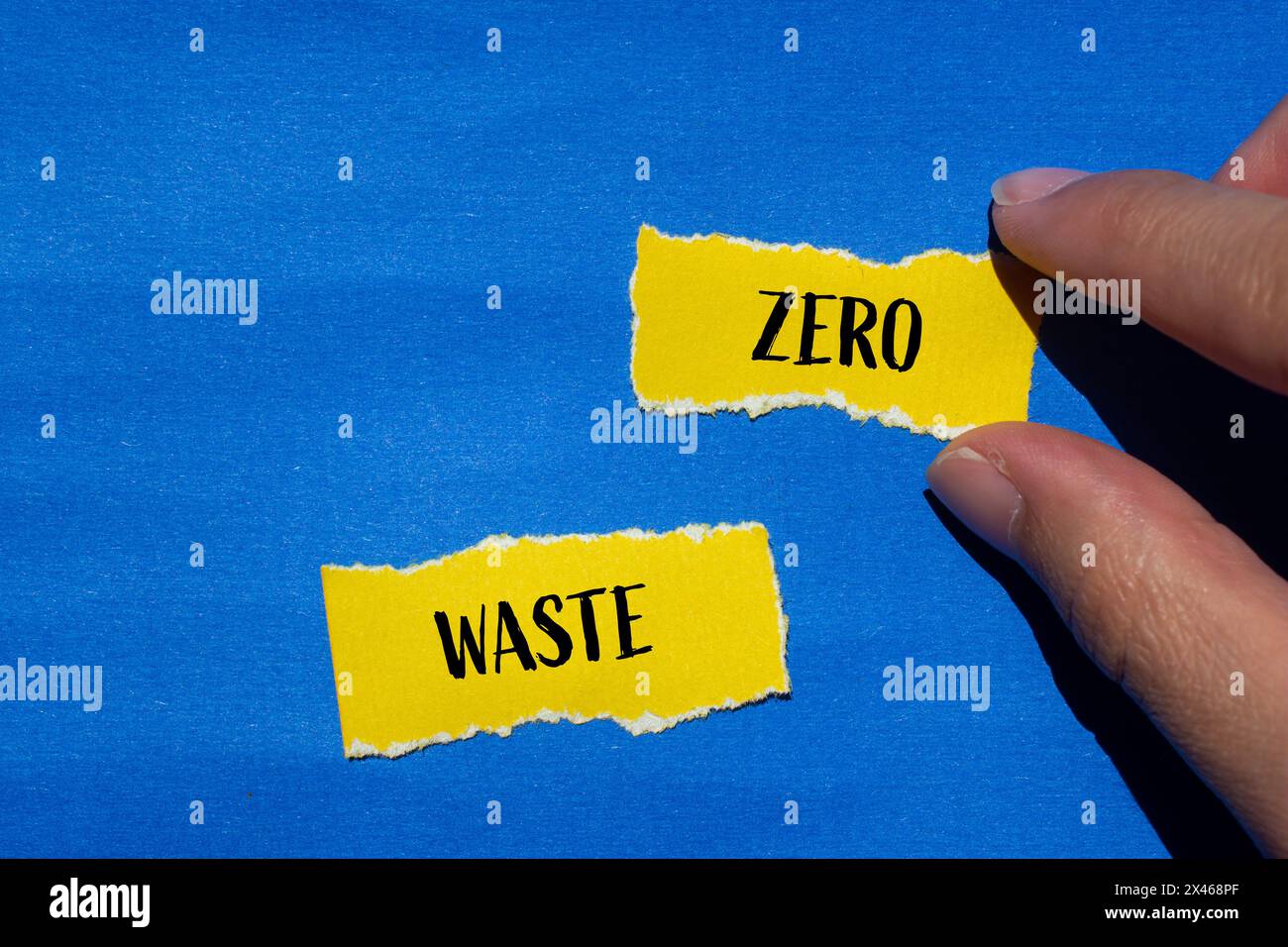 Zero waste written on ripped yellow paper pieces with blue background. Conceptual zero waste ...