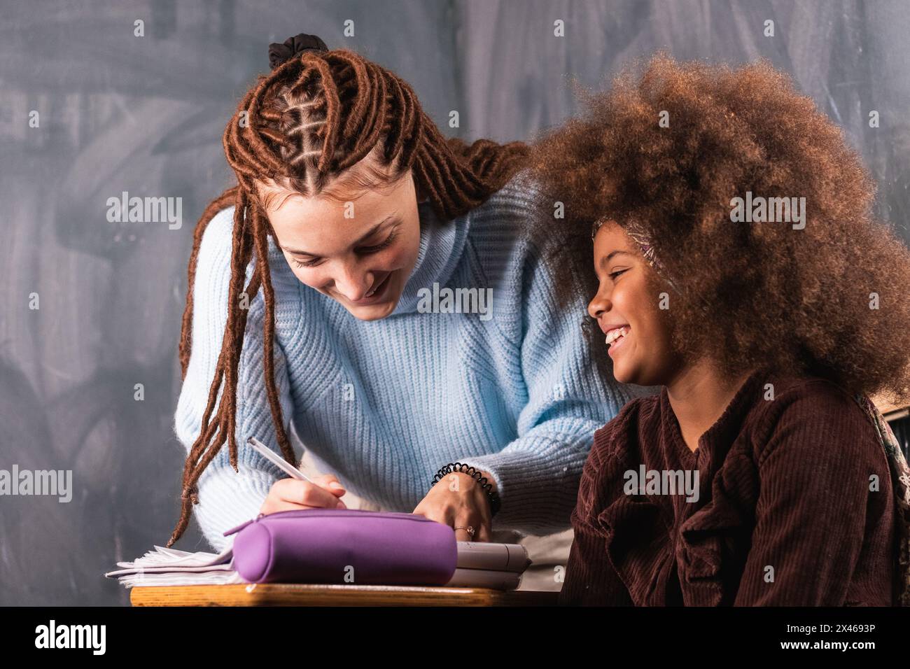 Cheerful African American pupil and teacher doing task together at ...