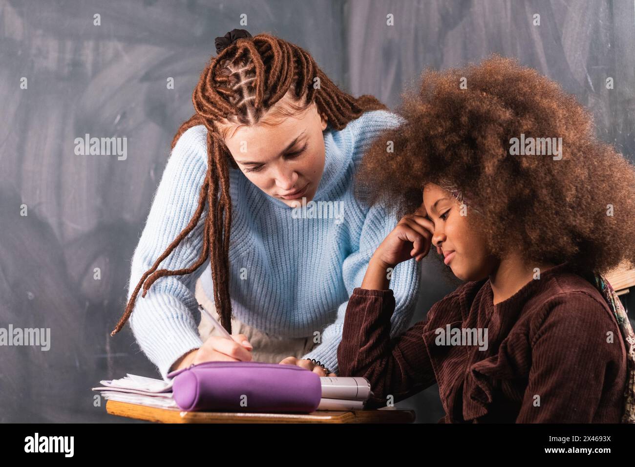 Cheerful African American pupil and teacher doing task together at ...