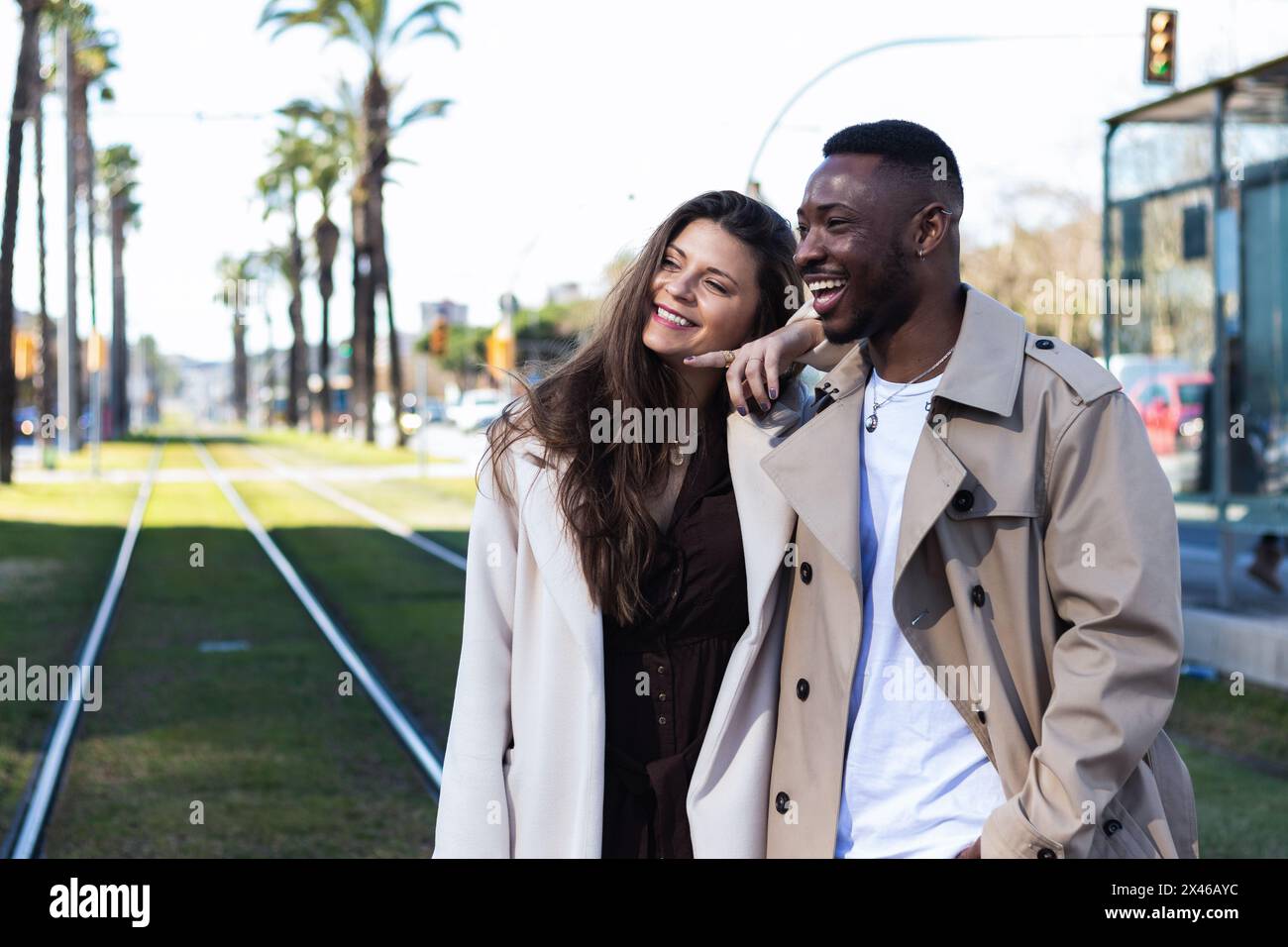 Cheerful adult multiracial couple in trendy coats walking together on ...