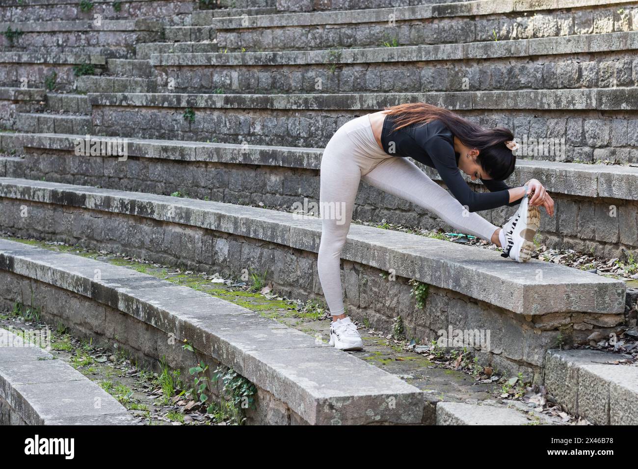 Flexible female in activewear doing forward bend while stretching legs ...