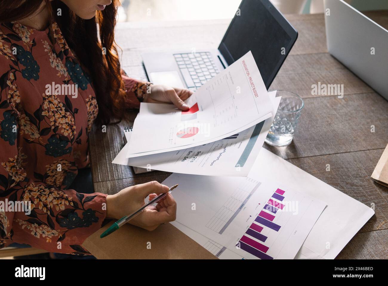 Crop focused female in stylish dress office worker analyzing diagrams ...