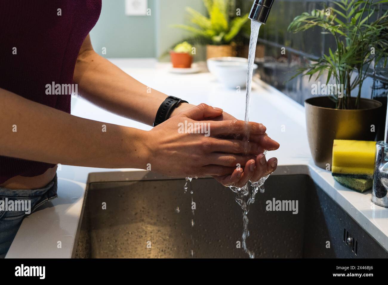 Crop unrecognizable female washing hands under pure water flow from tap ...