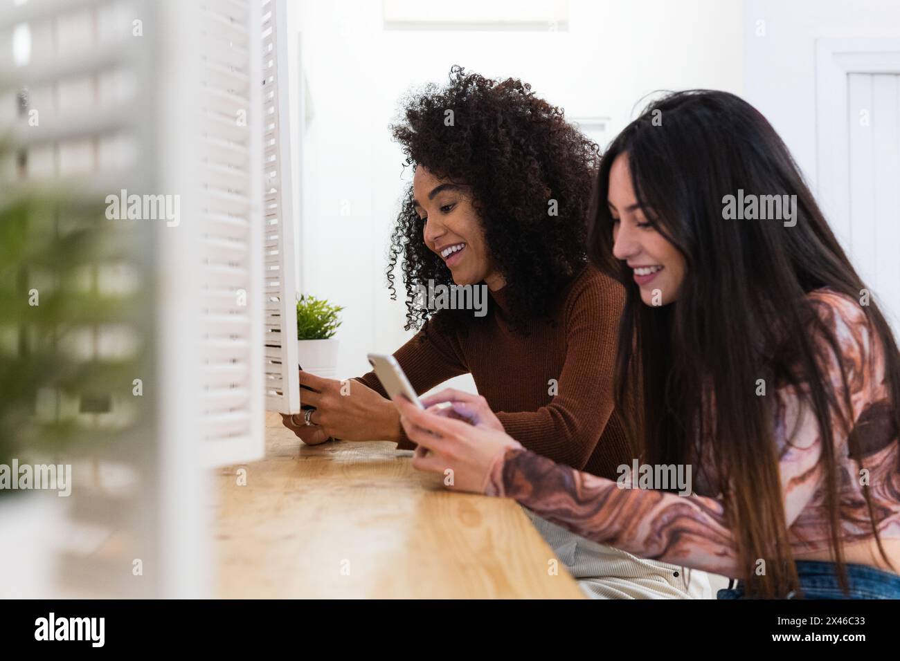 Side view of content diverse female friends sitting at counter in bar ...
