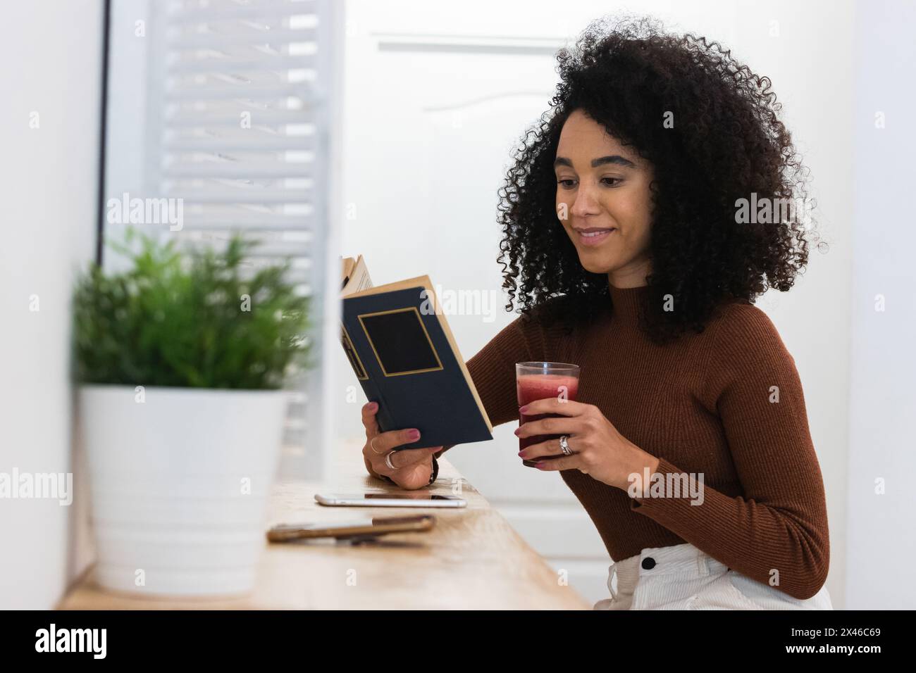 Side view of smiling black female sitting at counter in bar while ...