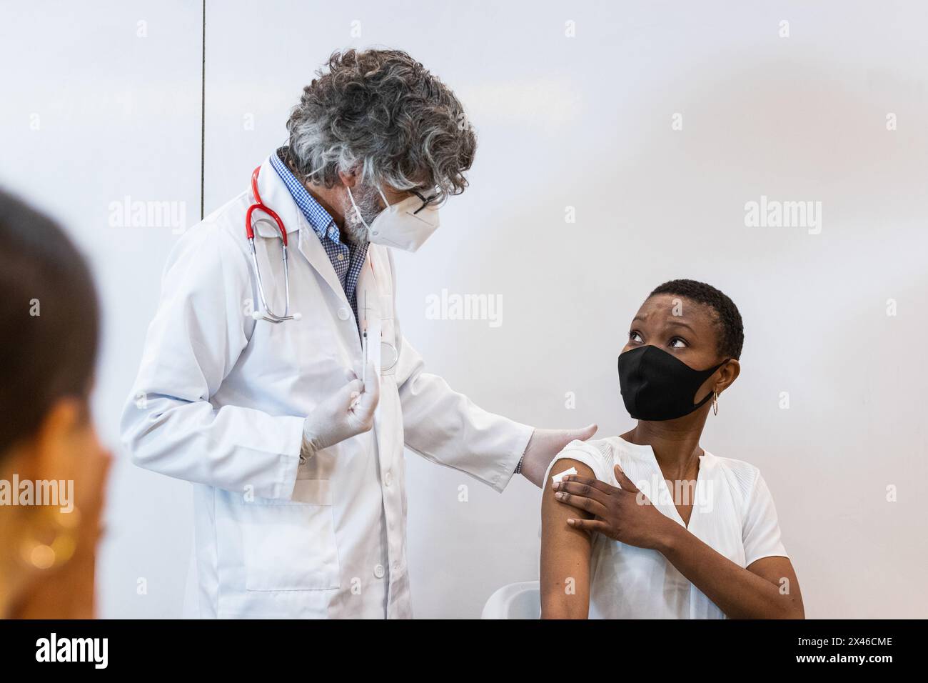 Male medic making injection for black female patient in mask Stock ...