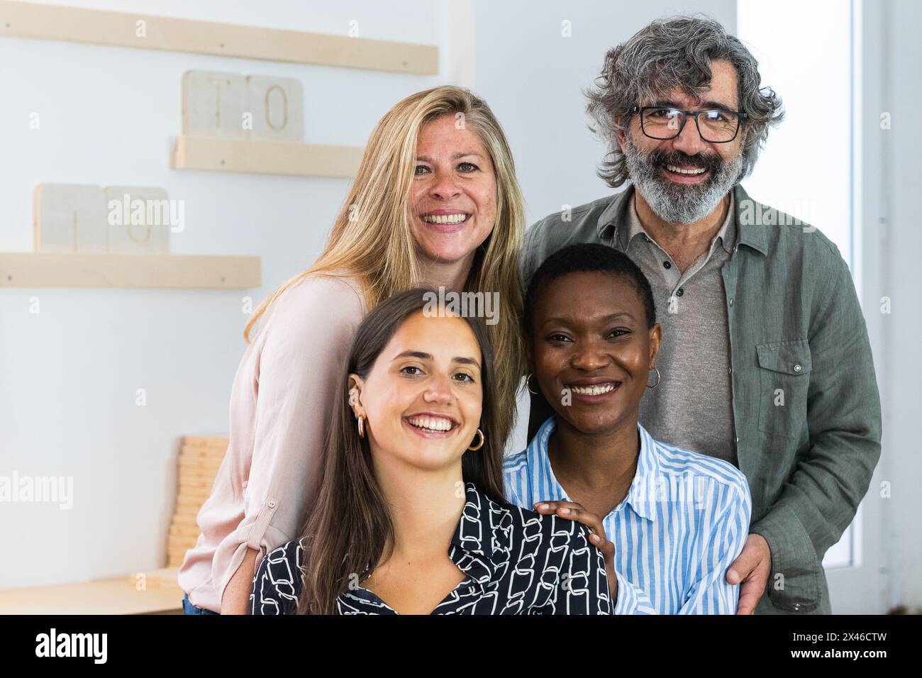 Delighted multiracial female colleagues looking at camera and smiling ...