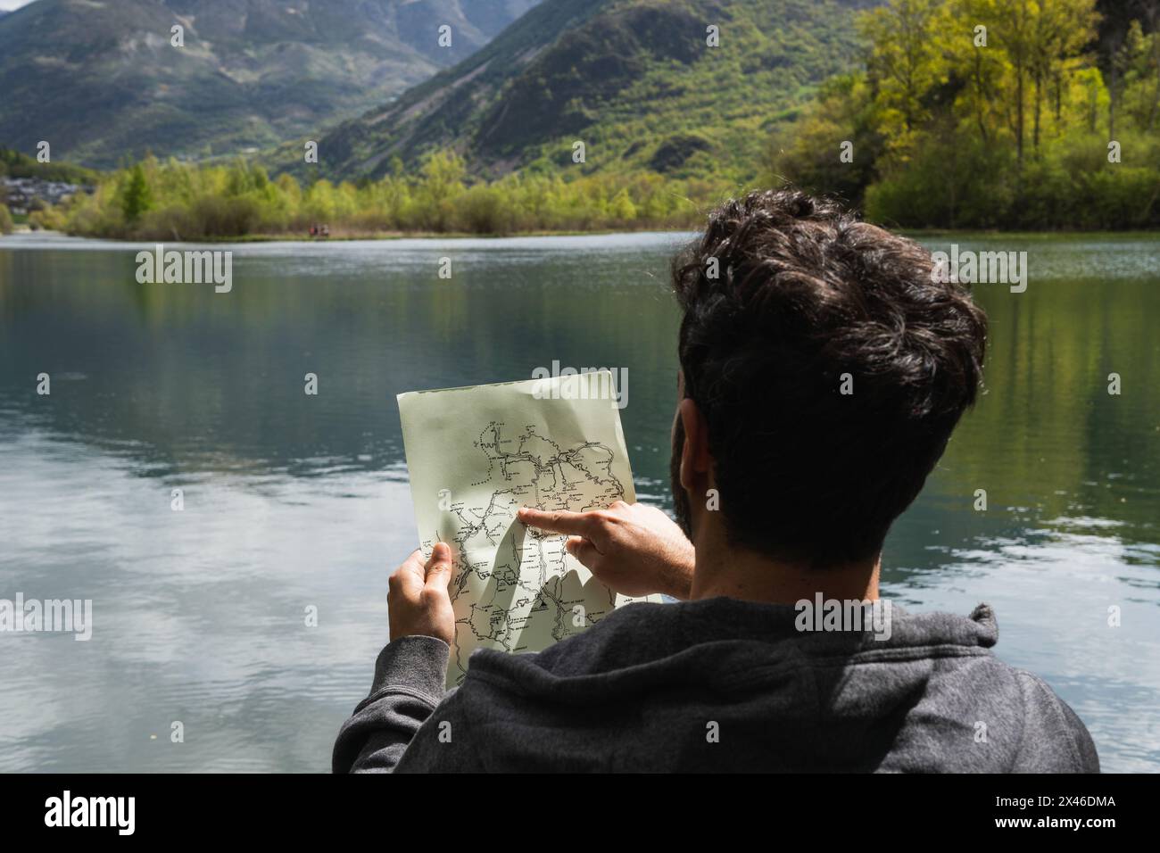 Back view of unrecognizable male explorer reading paper map and ...