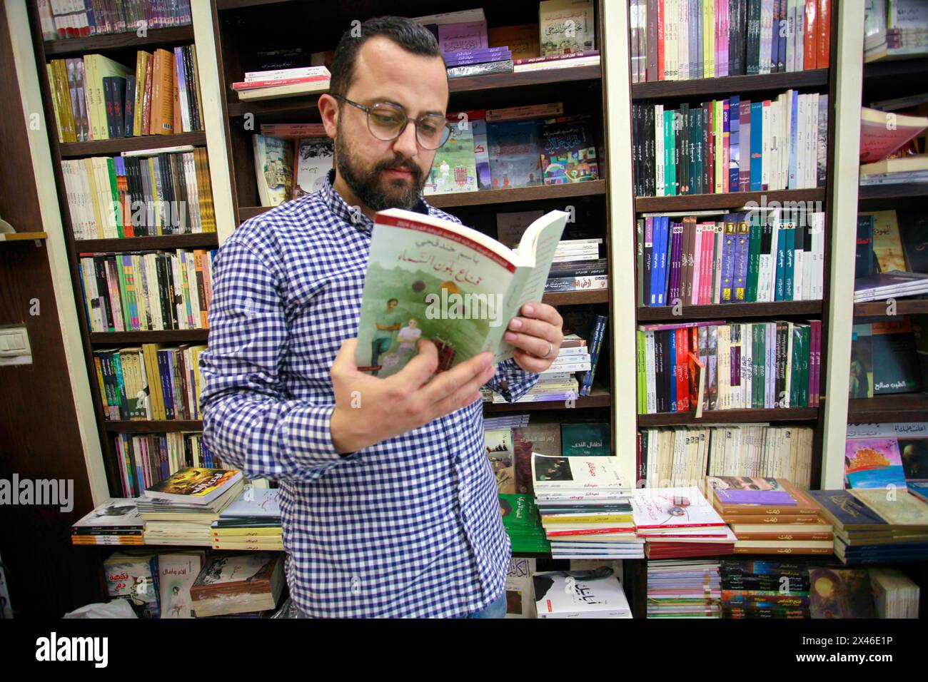 A man reads the book, "A Mask in the Color of the Sky" which won the Arab Booker Prize, the most ...