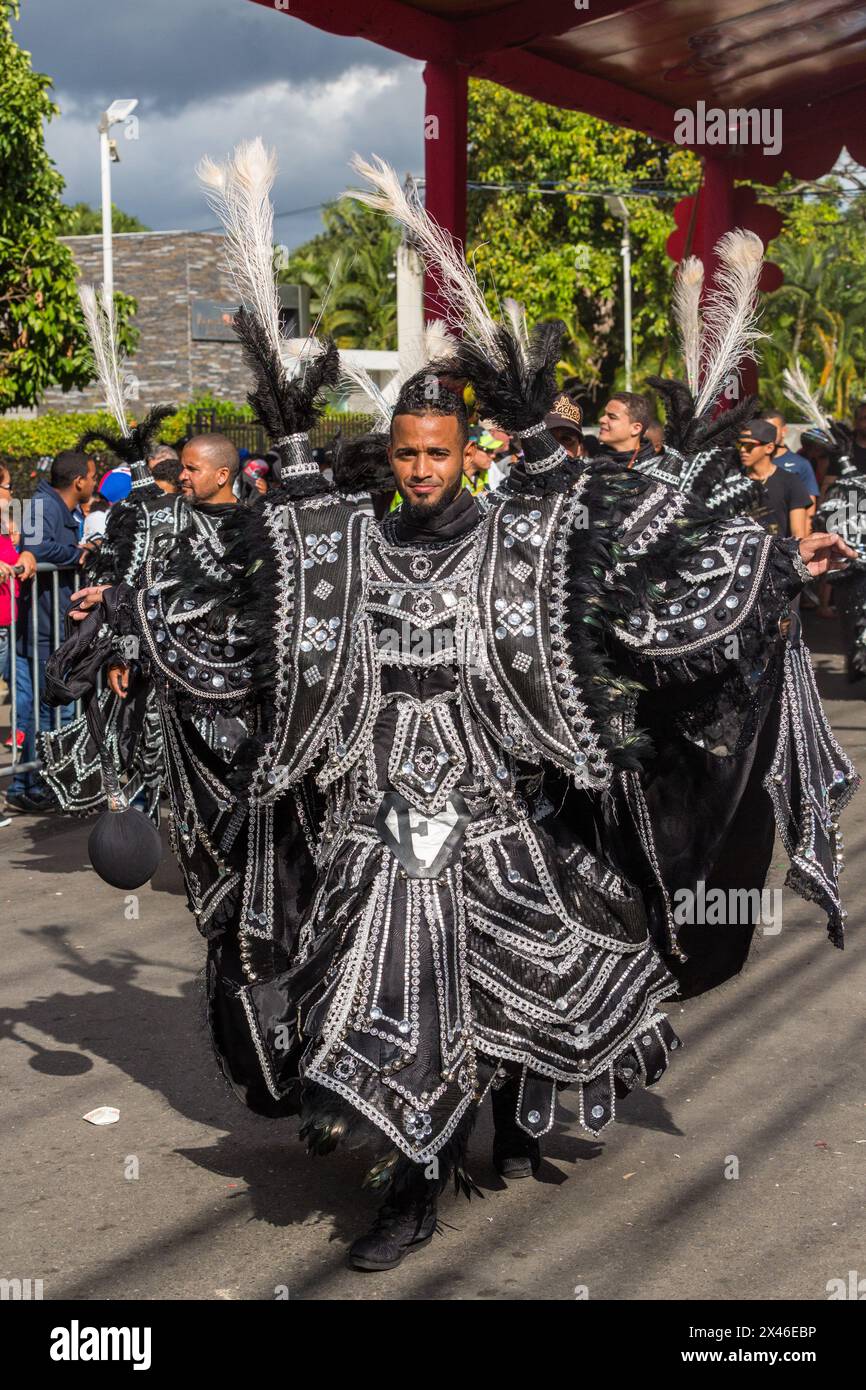 Young men in elaborate costumes march in the La Vega Carnival parade ...