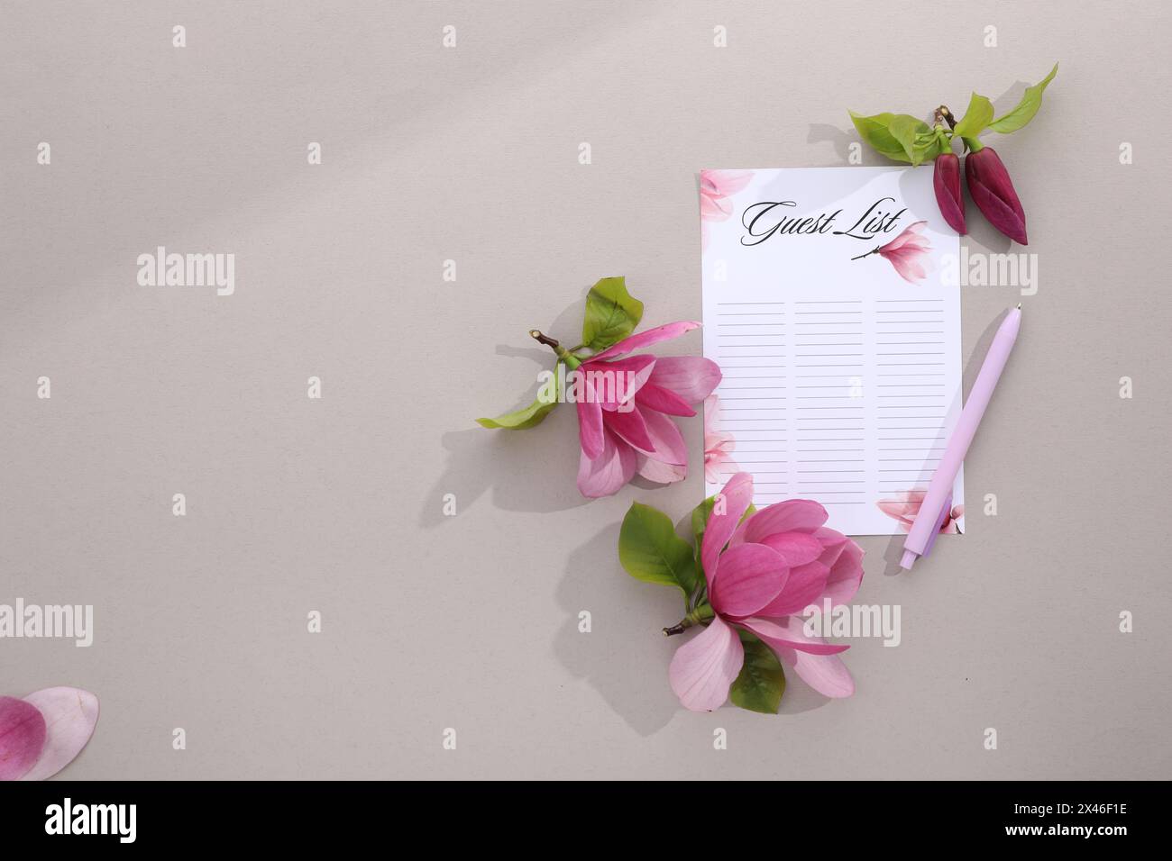 Guest list, pen and beautiful flowers on grey background, flat lay ...