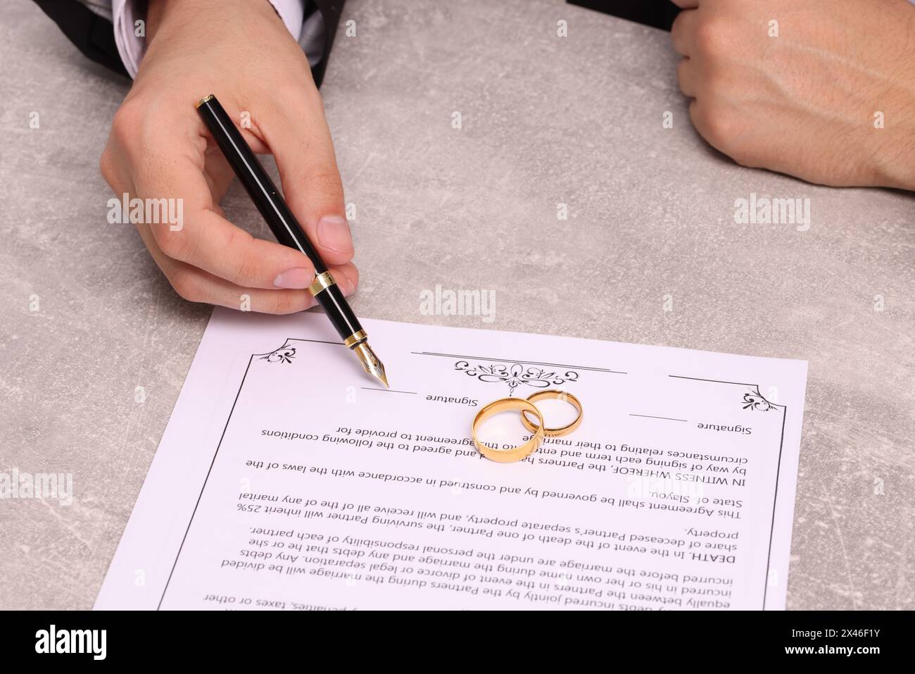 Man signing marriage contract at light grey table, closeup Stock Photo ...
