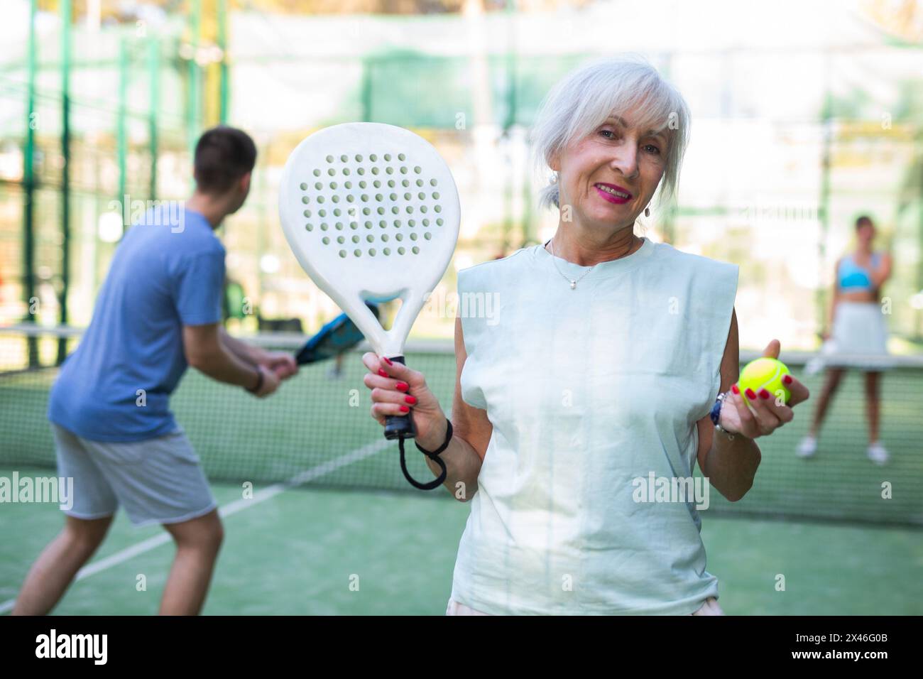 Portrait of positive senior woman on padel tennis court Stock Photo - Alamy