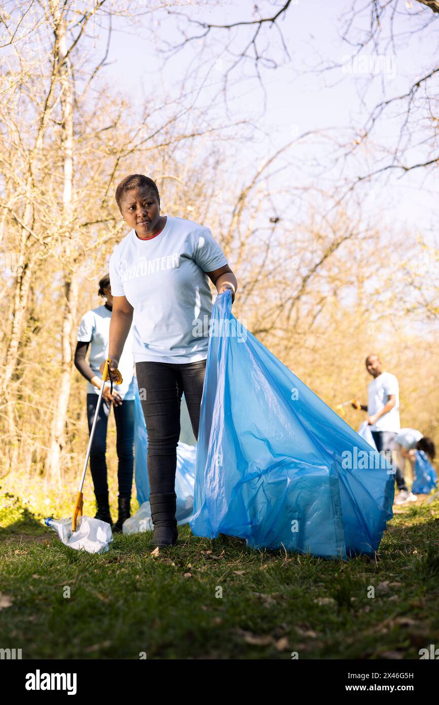 African american volunteer tidying the woods area of garbage and ...