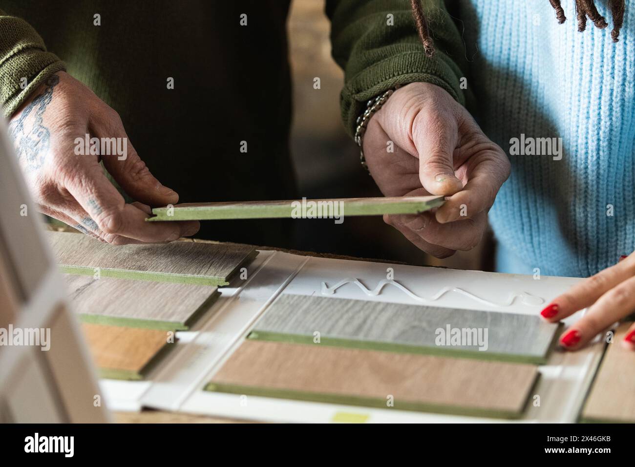 Cropped unrecognizable craftsman helping female client in picking ...