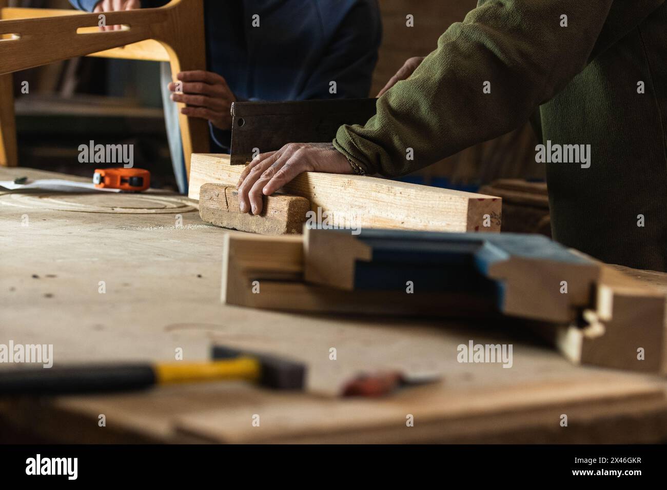 Unrecognizable carpenters cutting with saw and measuring woodwork with ...