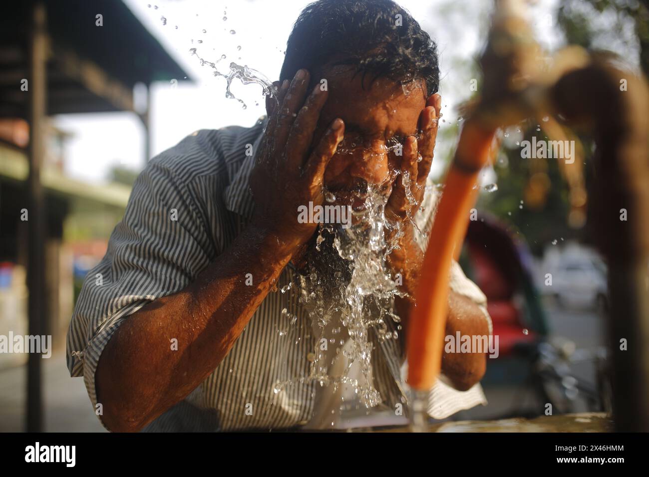 A Man Is Wetting His Face At A Roadside Tap To Get Relief From A